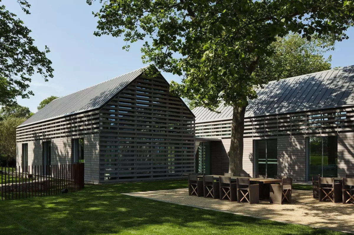သစ်သားပြားဖြင့်ဖုံးအုပ်ထားသော မှန်ချပ်များသည် ဤ Hamptons ဧည့်သည်အိမ်တွင် အံဝင်ခွင်ကျရှိသော အတွင်းပိုင်းကို ဖန်တီးပေးသည်။ 17143_1