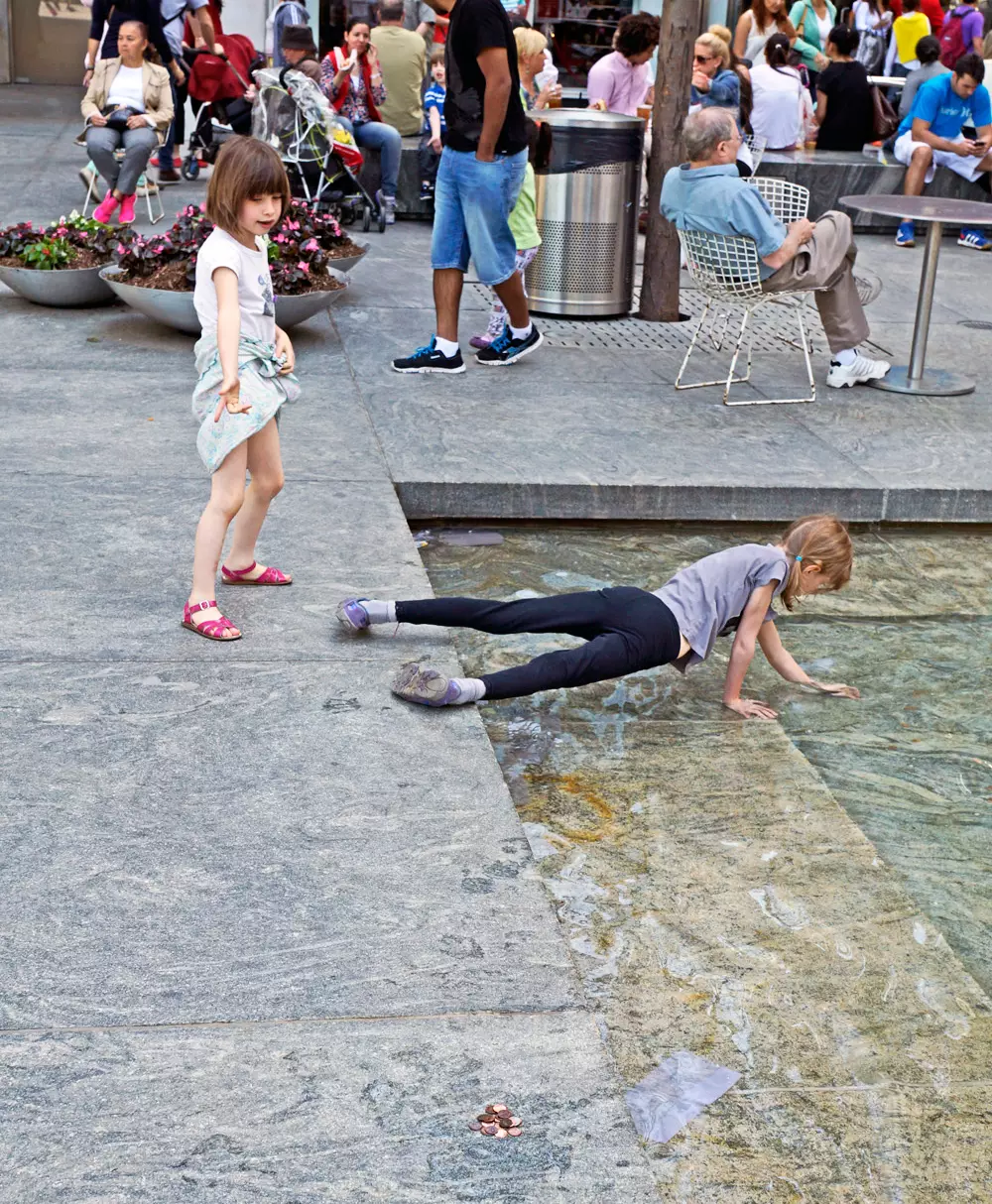 mladé dievča, ktoré loví centy z bazéna na námestí